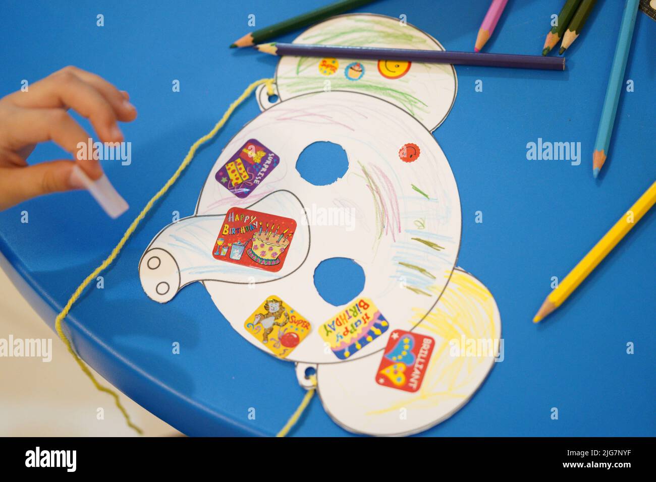 A little child coloring an animal paper mask in the classroom. elephant ...