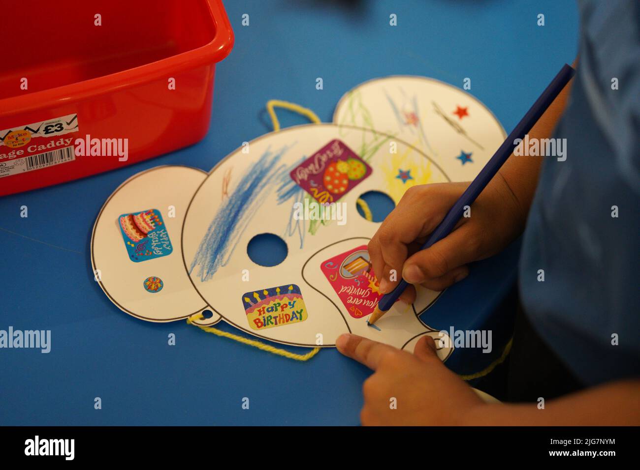 A little child coloring an animal paper mask in the classroom. elephant ...