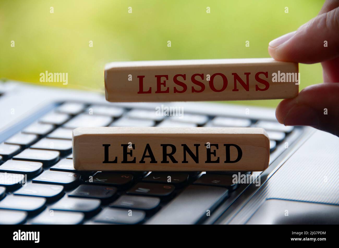 Hand holding lessons learned text on wooden blocks on top of a laptop ...