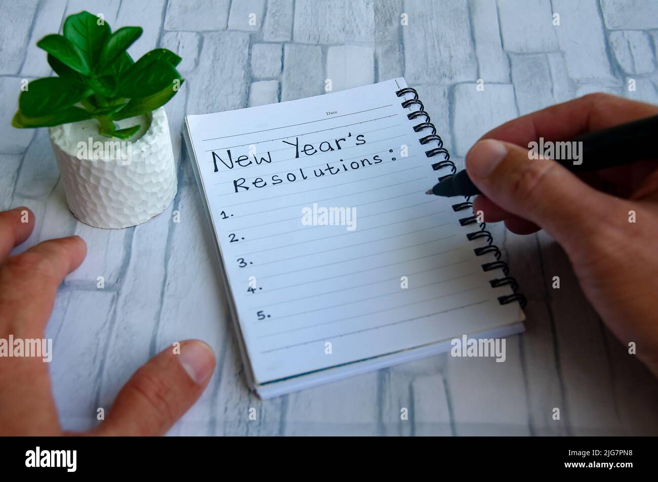 Hand writing New Year's Resolutions text on notepad. New year's ...