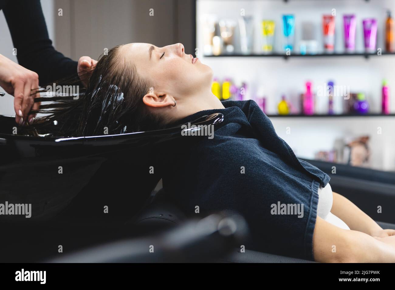 Master woman hairdresser gently washes the girl's hair with shampoo and ...