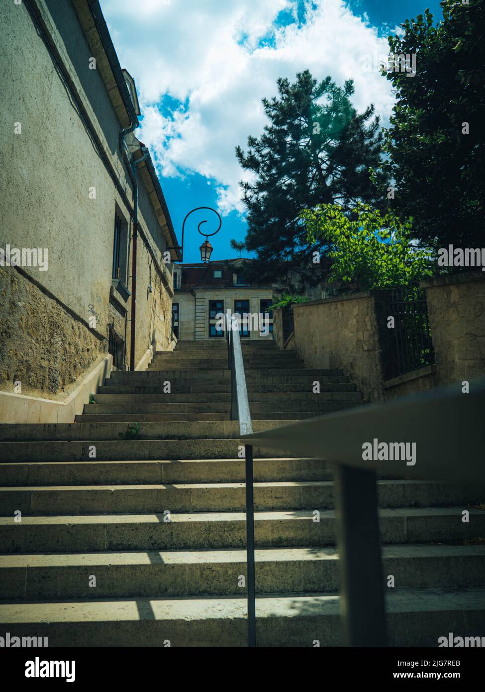 A vertical shot of a staircase with fence outdoor between buildings and ...