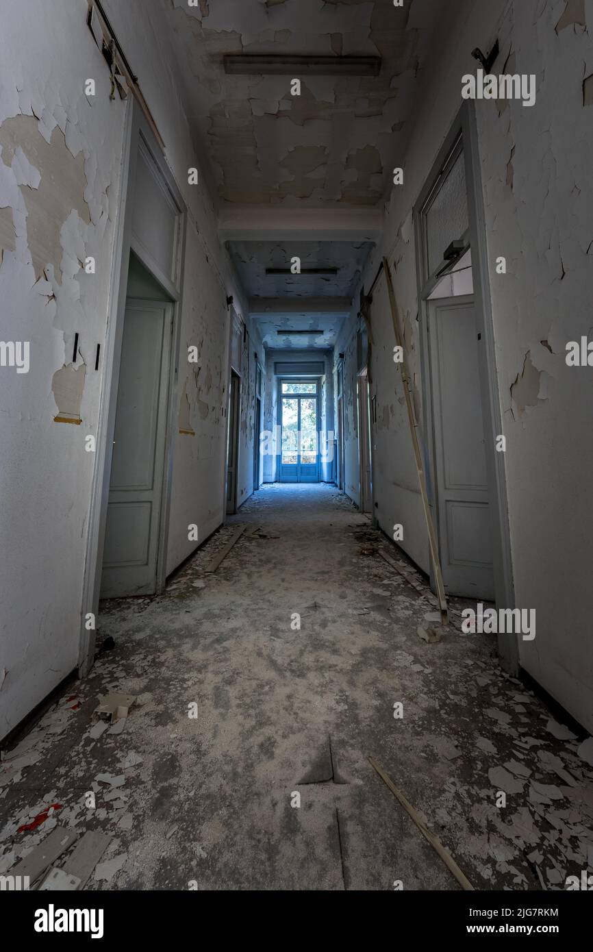 A vertical shot of a hallway with a window in an abandoned building ...