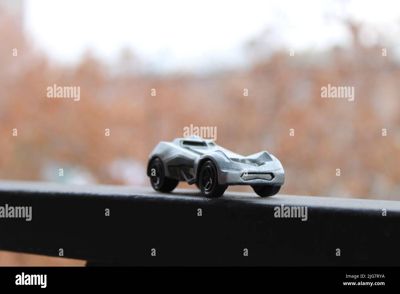 A gray sporty car toy with blurred autumn trees on the horizon Stock ...