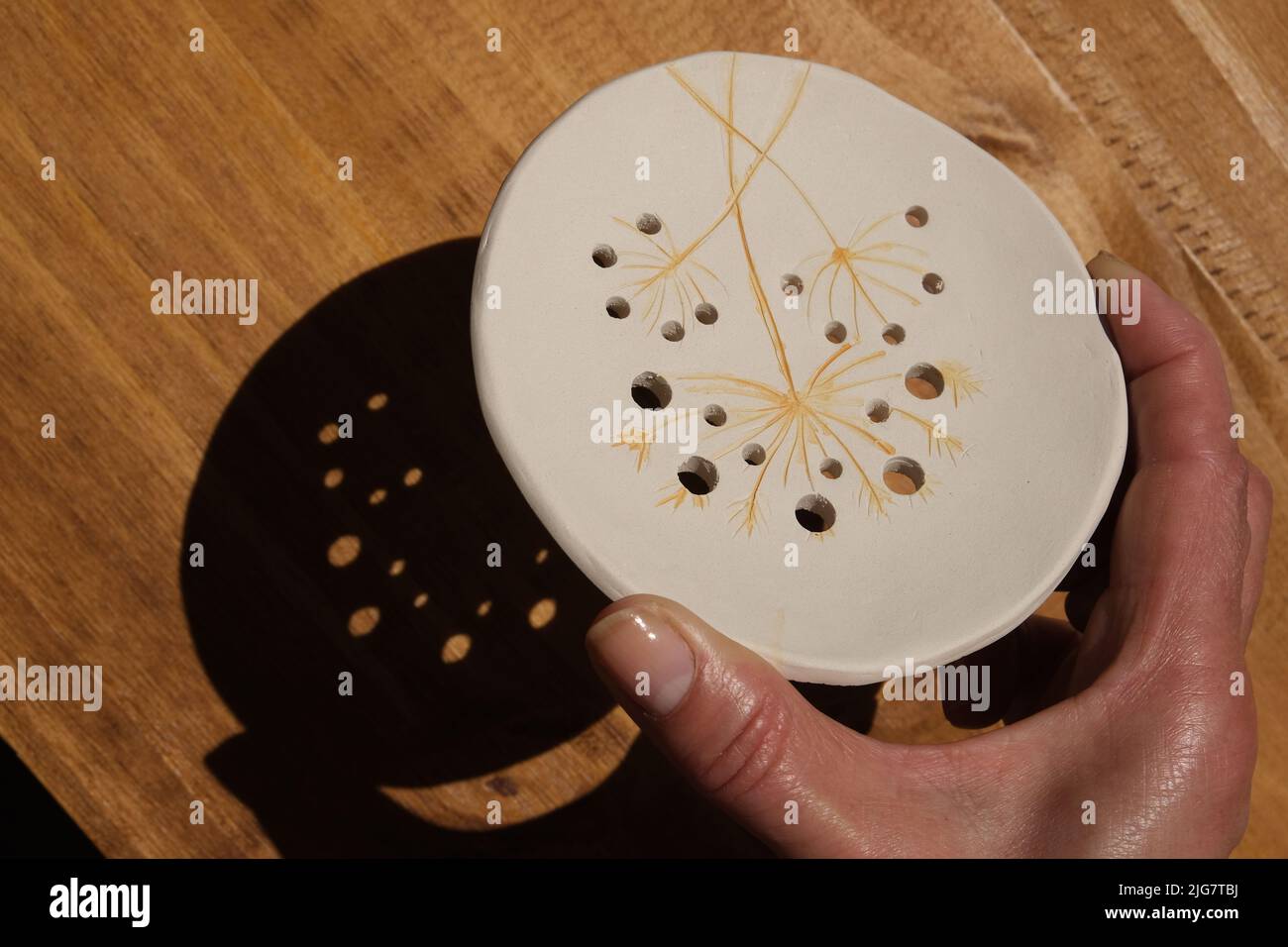 A top view of ceramic craft in a hand on wooden background Stock Photo ...