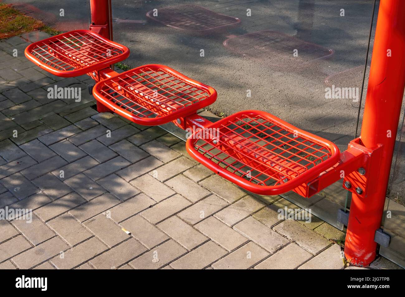 Red, metal bus stop seats on the street in daylight Stock Photo - Alamy
