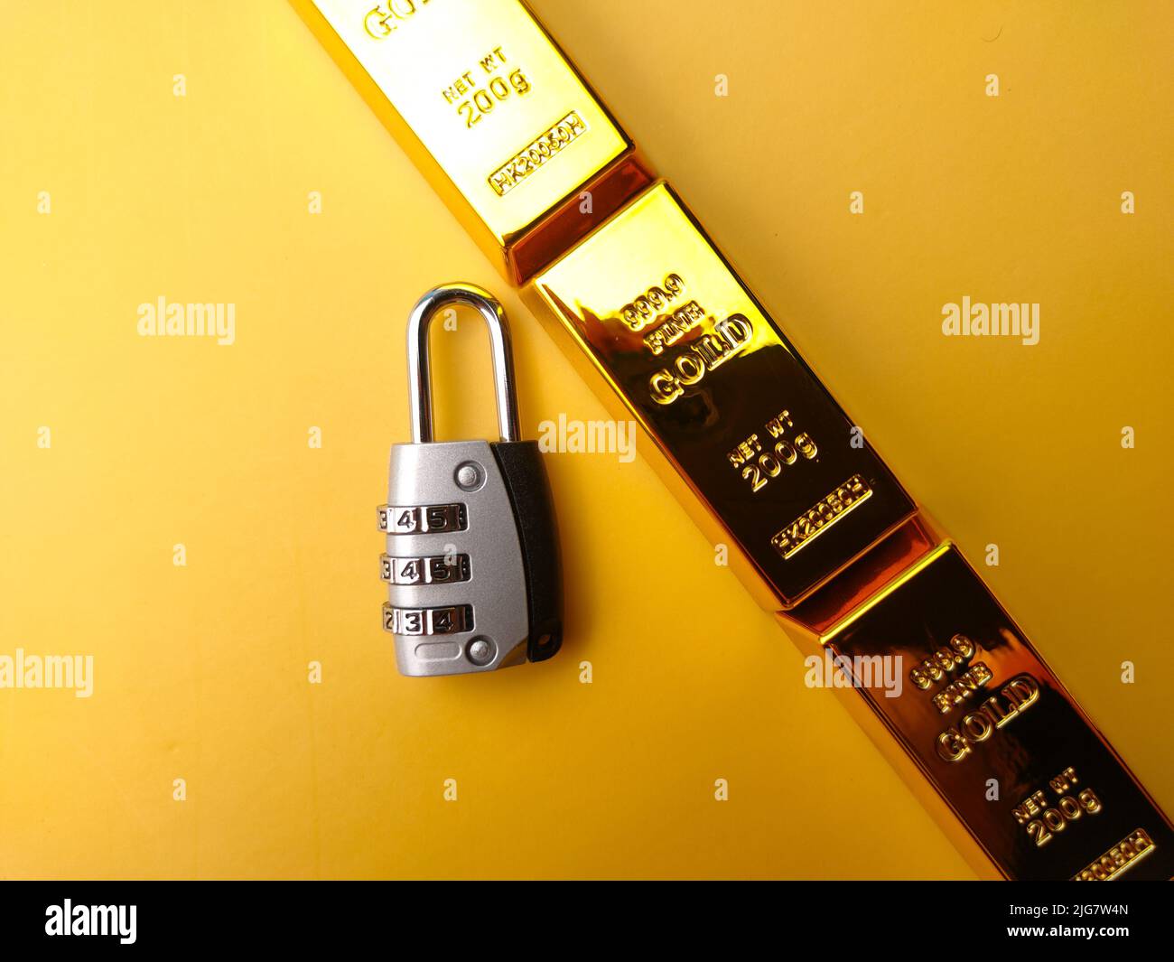 Three gold bars and a padlock isolated on a yellow background - finance ...