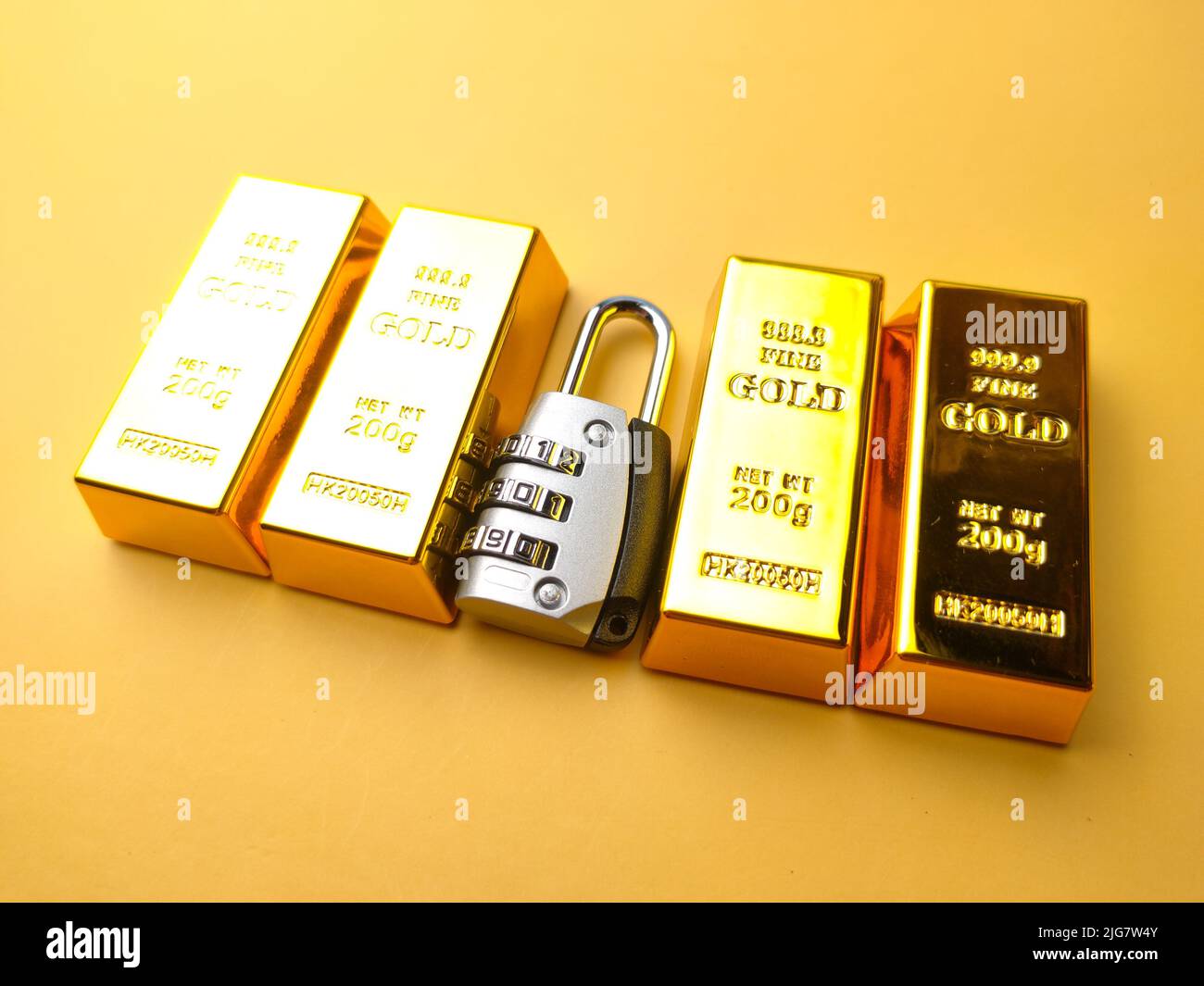 Four gold bars and a padlock isolated on a yellow background - finance ...