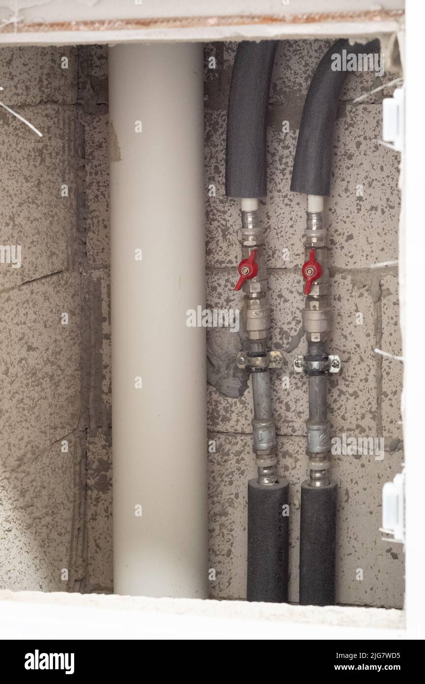 Water pipes with red faucets go inside a new high-rise building. New ...