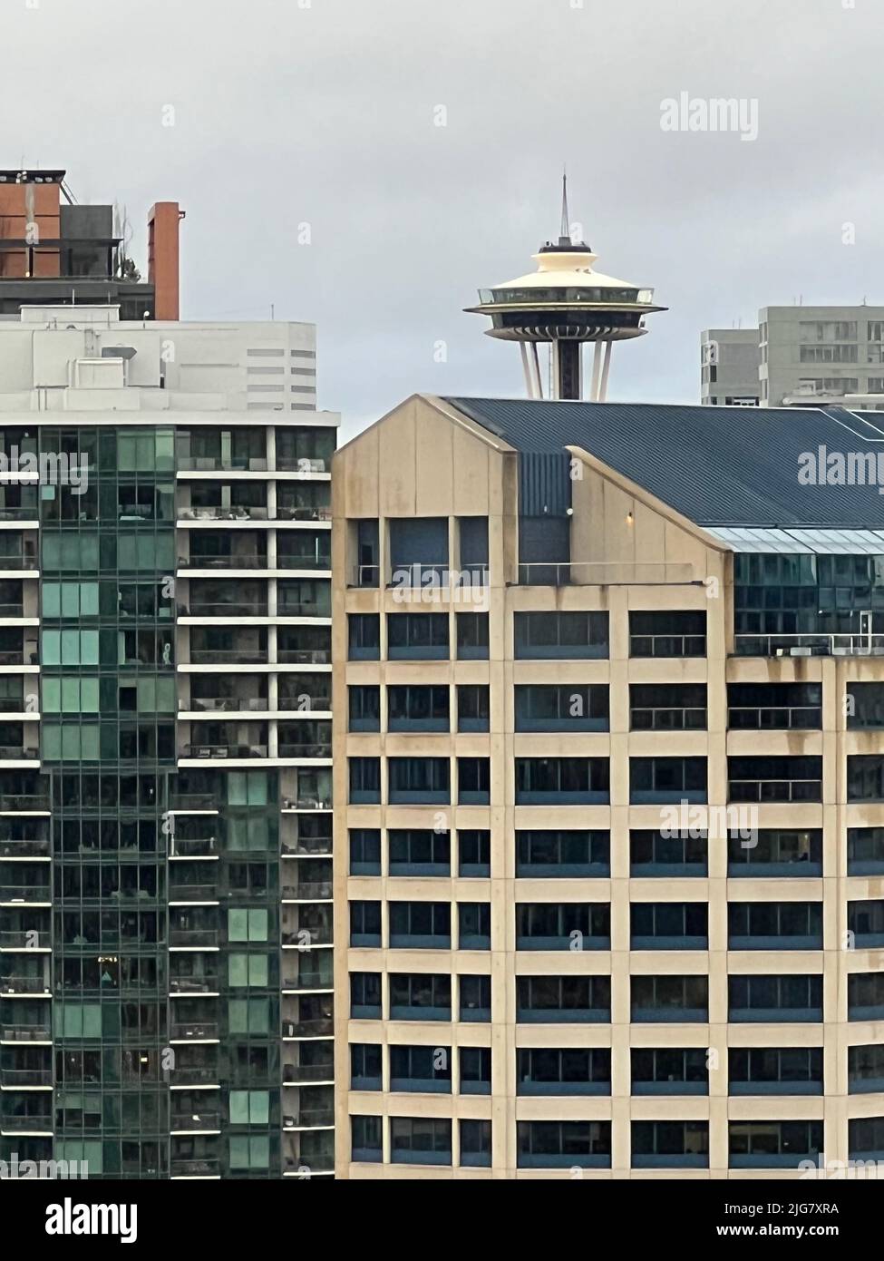 A vertical shot of the top of Space Needle among the modern buildings ...