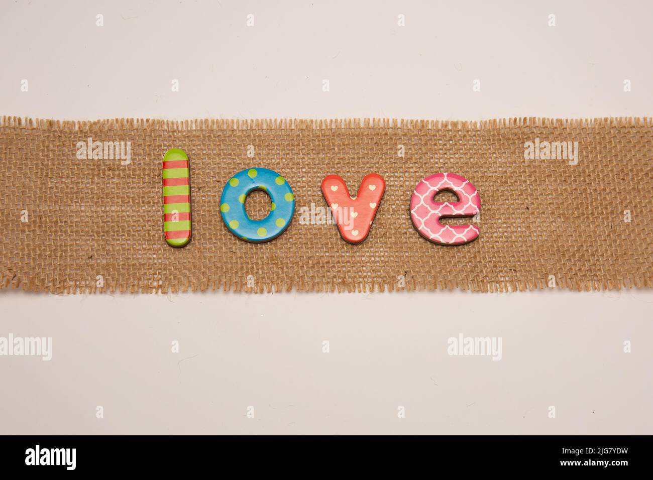The word "Love" in colorful letter tiles laid on Hessian jute cloth ...