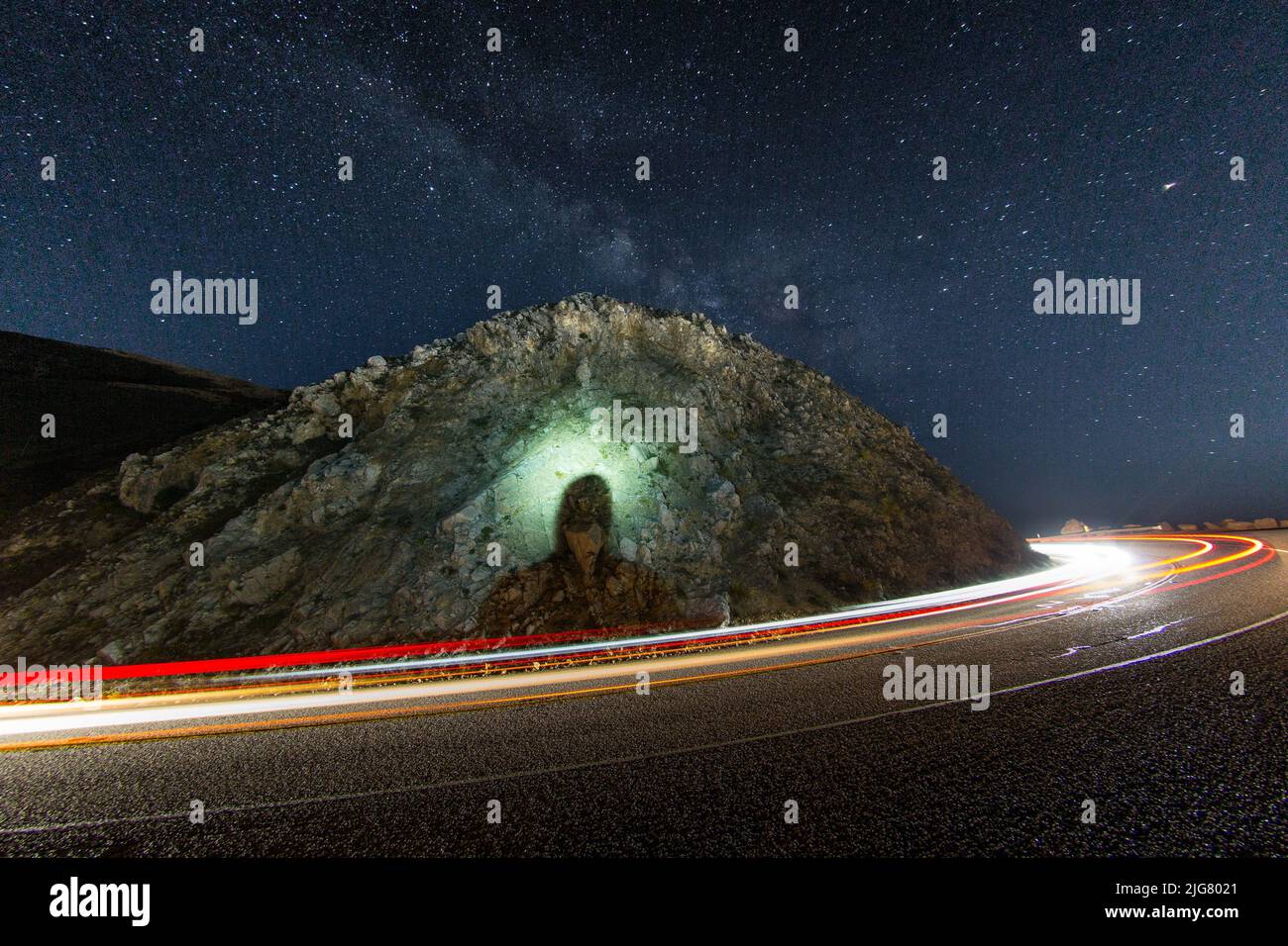 A shadow of a human on a hill and a curved road with a long exposure ...