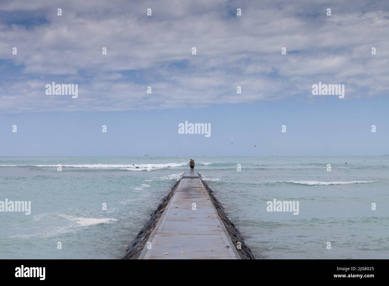 A jetty breaking seawater with people on the bottom looking over the ...