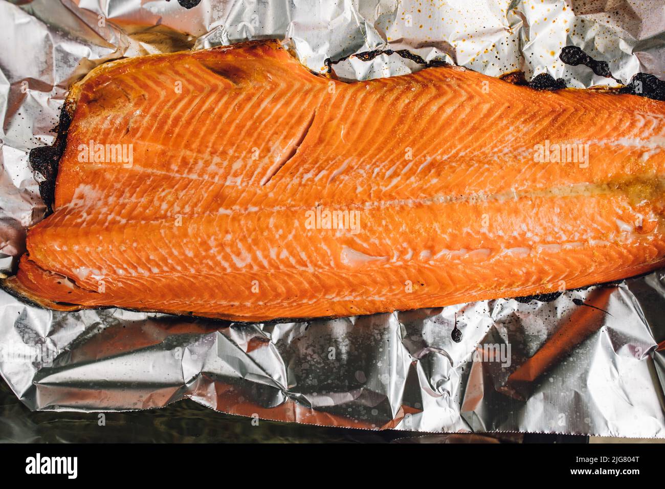 whole cooked, barbecued Copper River Salmon fillet on foil on the grill ...