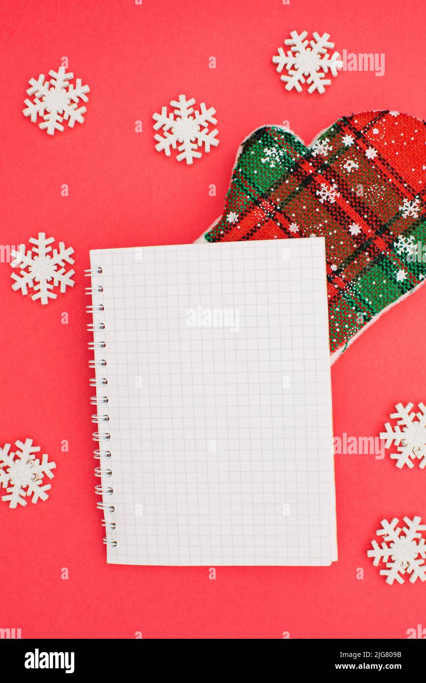 a shot of a notebook with winter glove and snowflakes on a pink ...