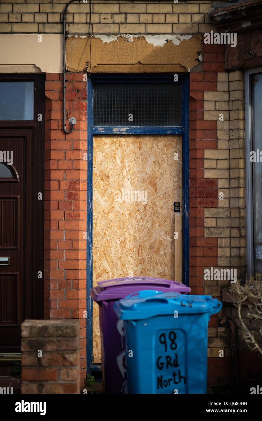 A vertical shot of garbage bins in front of a brown door of a ...