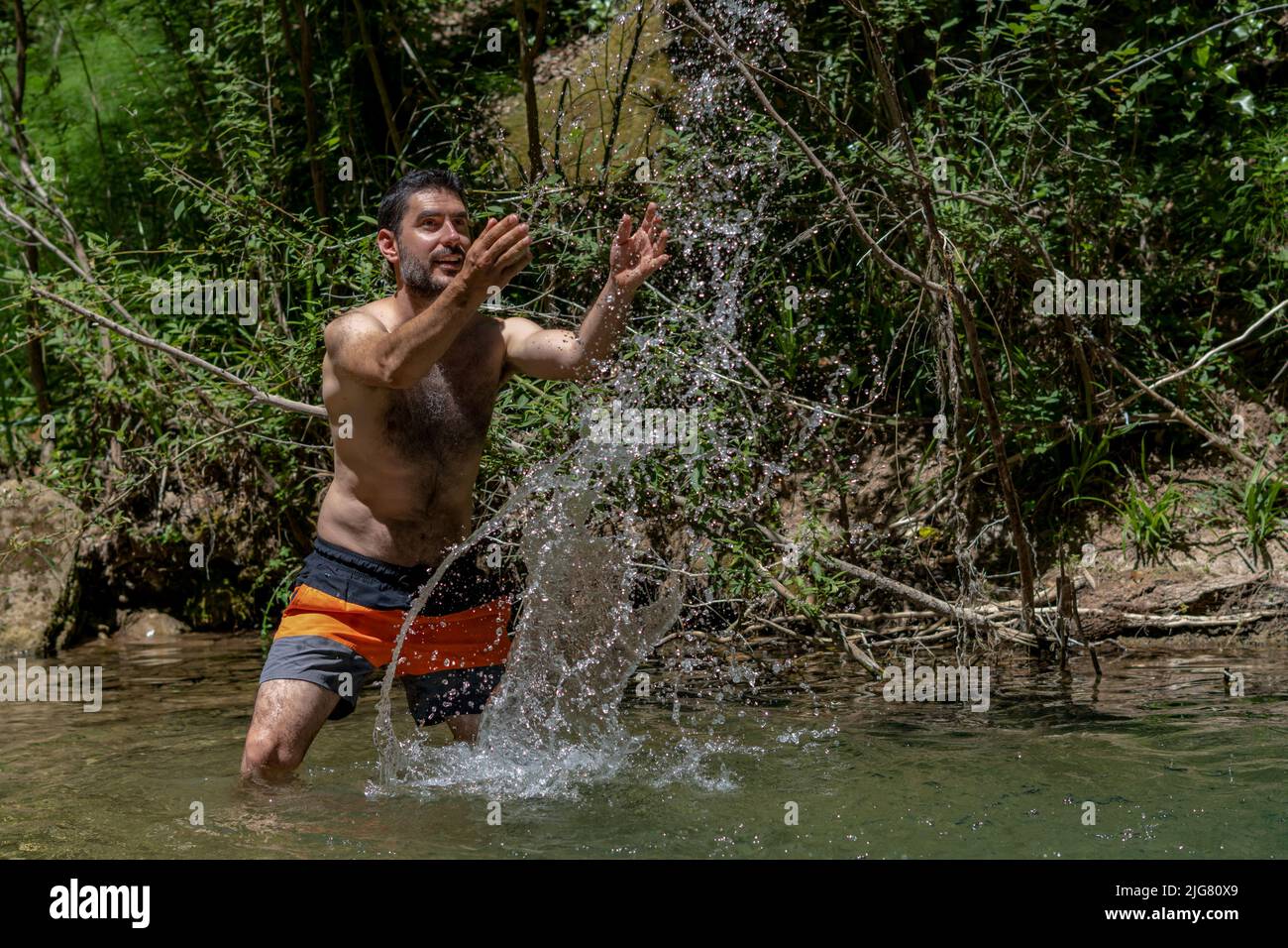 young man in the river in swimsuit splashing water with his hands Stock ...