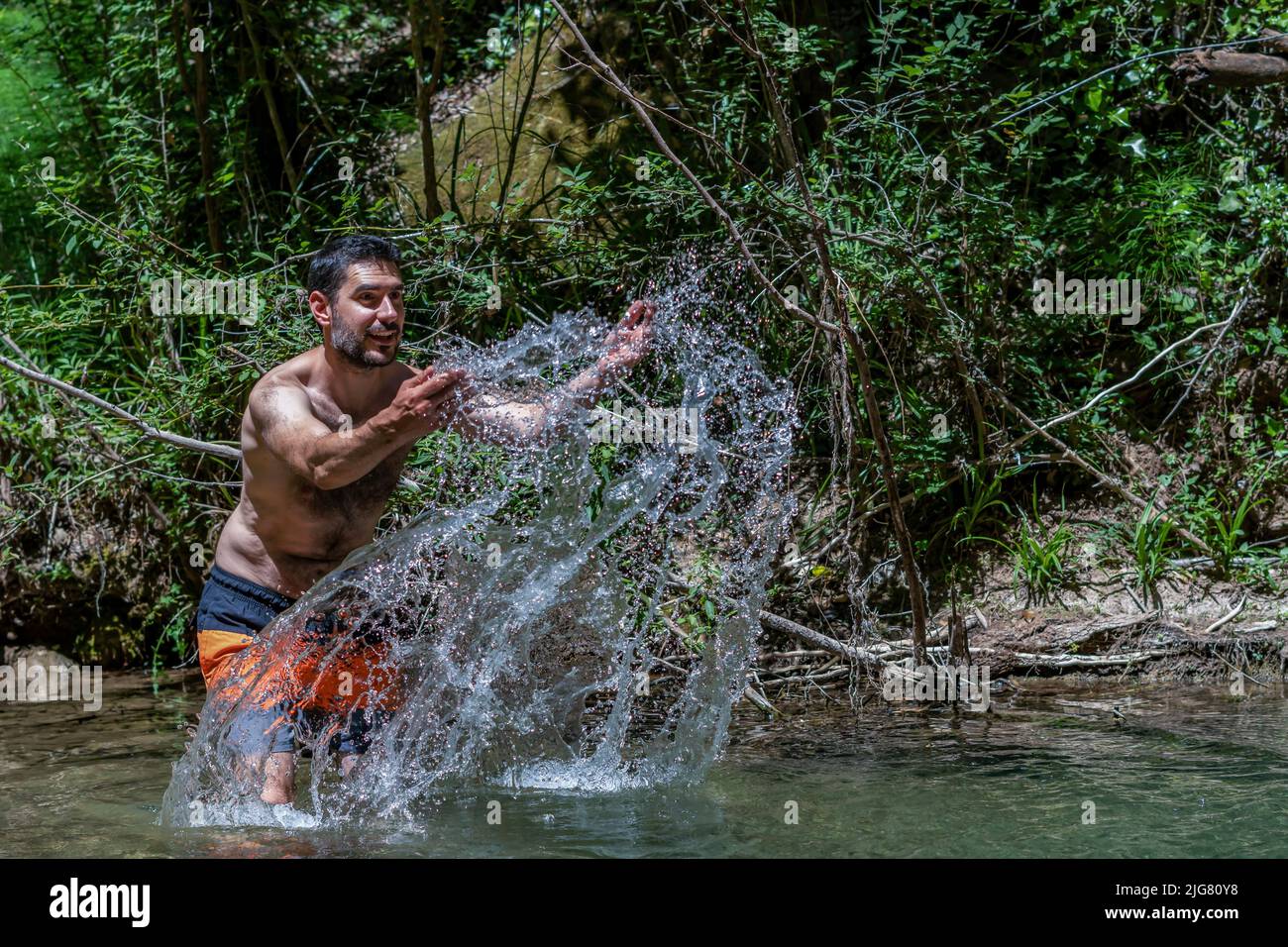 young man in the river in swimsuit splashing water with his hands Stock ...