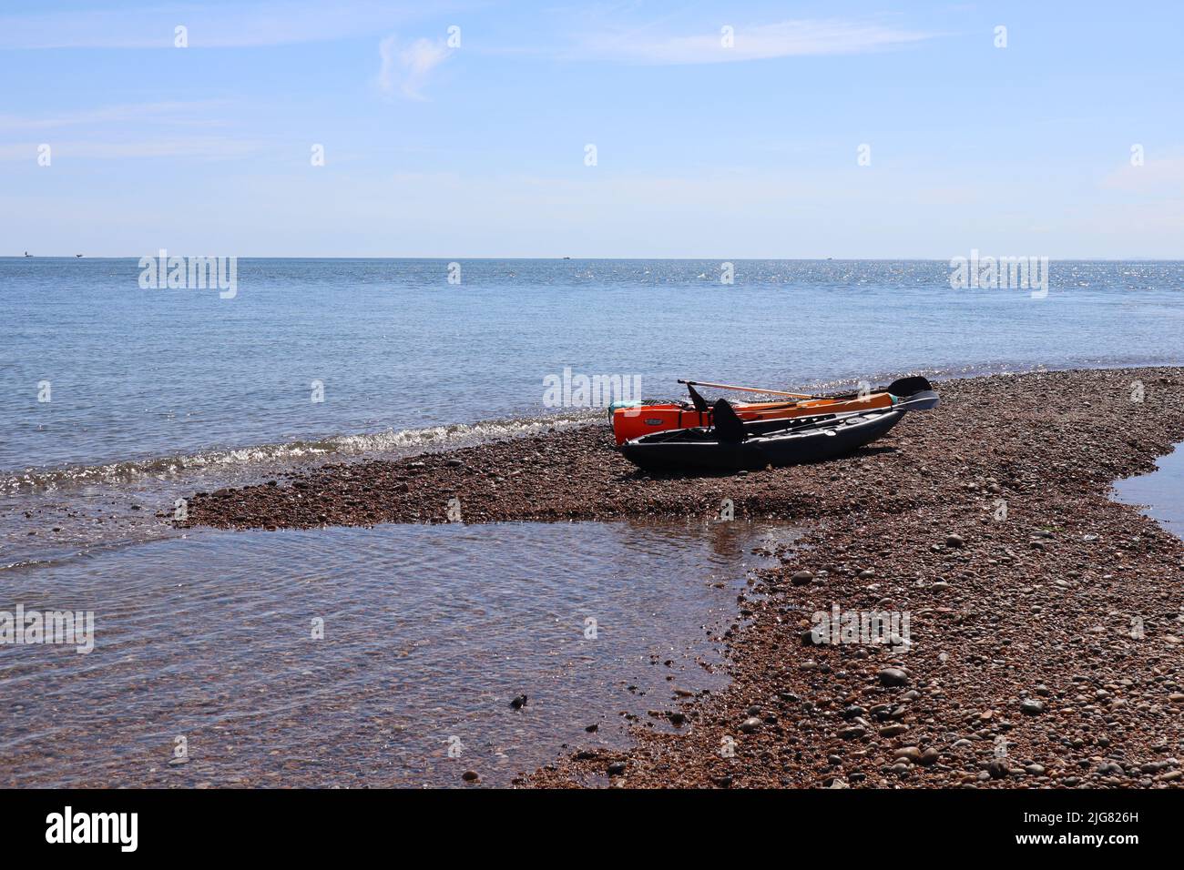 Three canoes rest on the edge of the shingle beach at the mouth of the ...