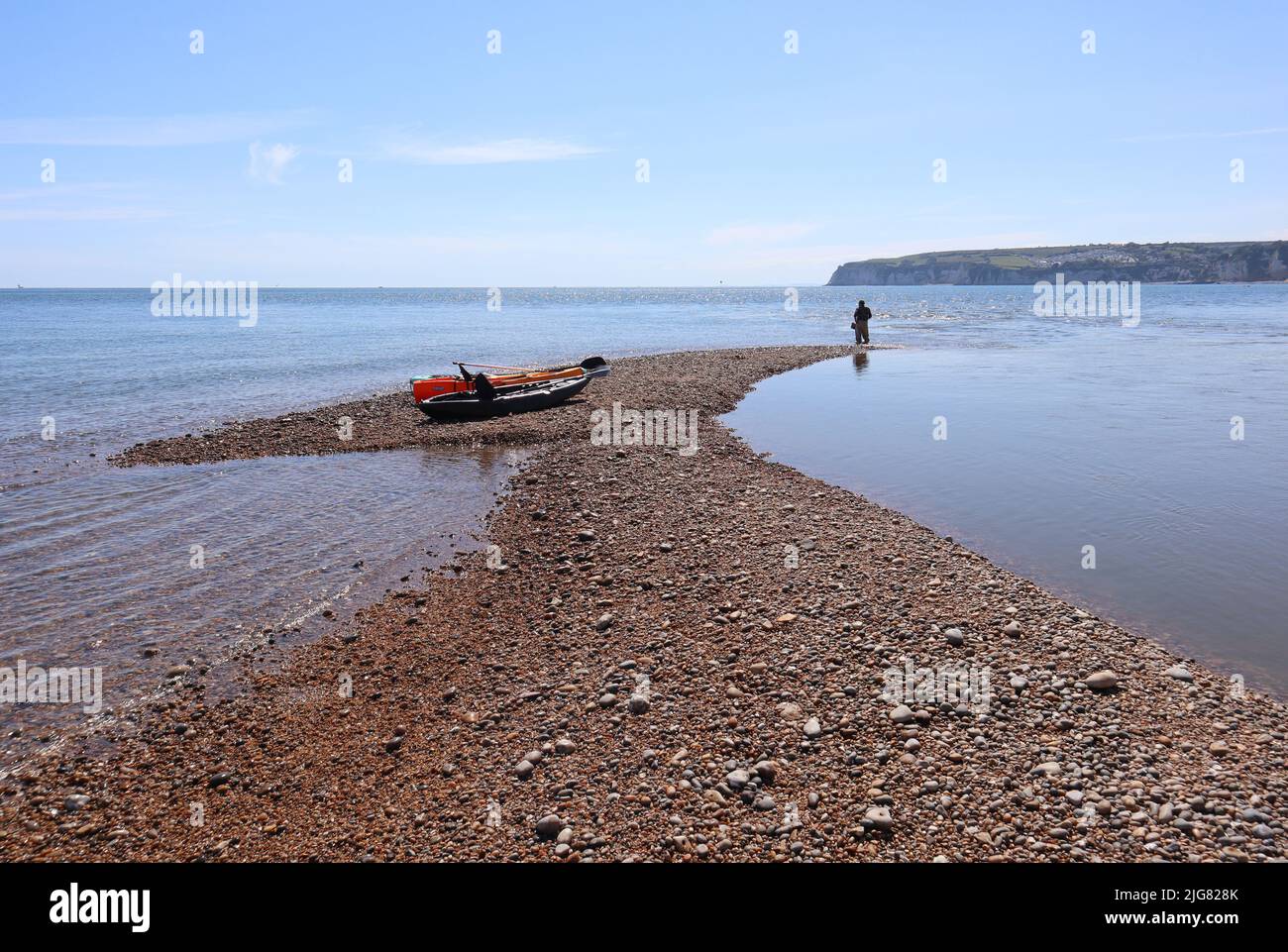 Three canoes rest on the edge of the shingle beach at the mouth of the ...