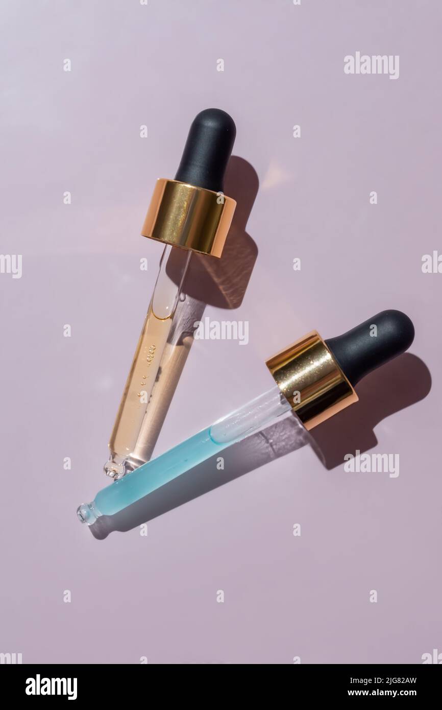 Transparent pipettes with blue and yellow cosmetics serum on a light ...