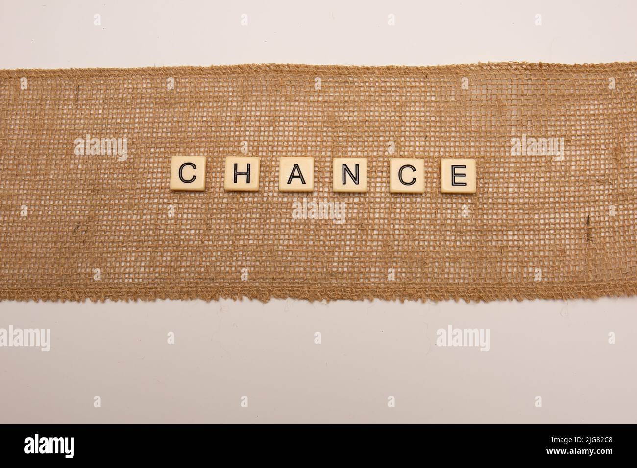 A "CHANCE" concept in letter tiles laid on Hessian jute cloth isolated ...