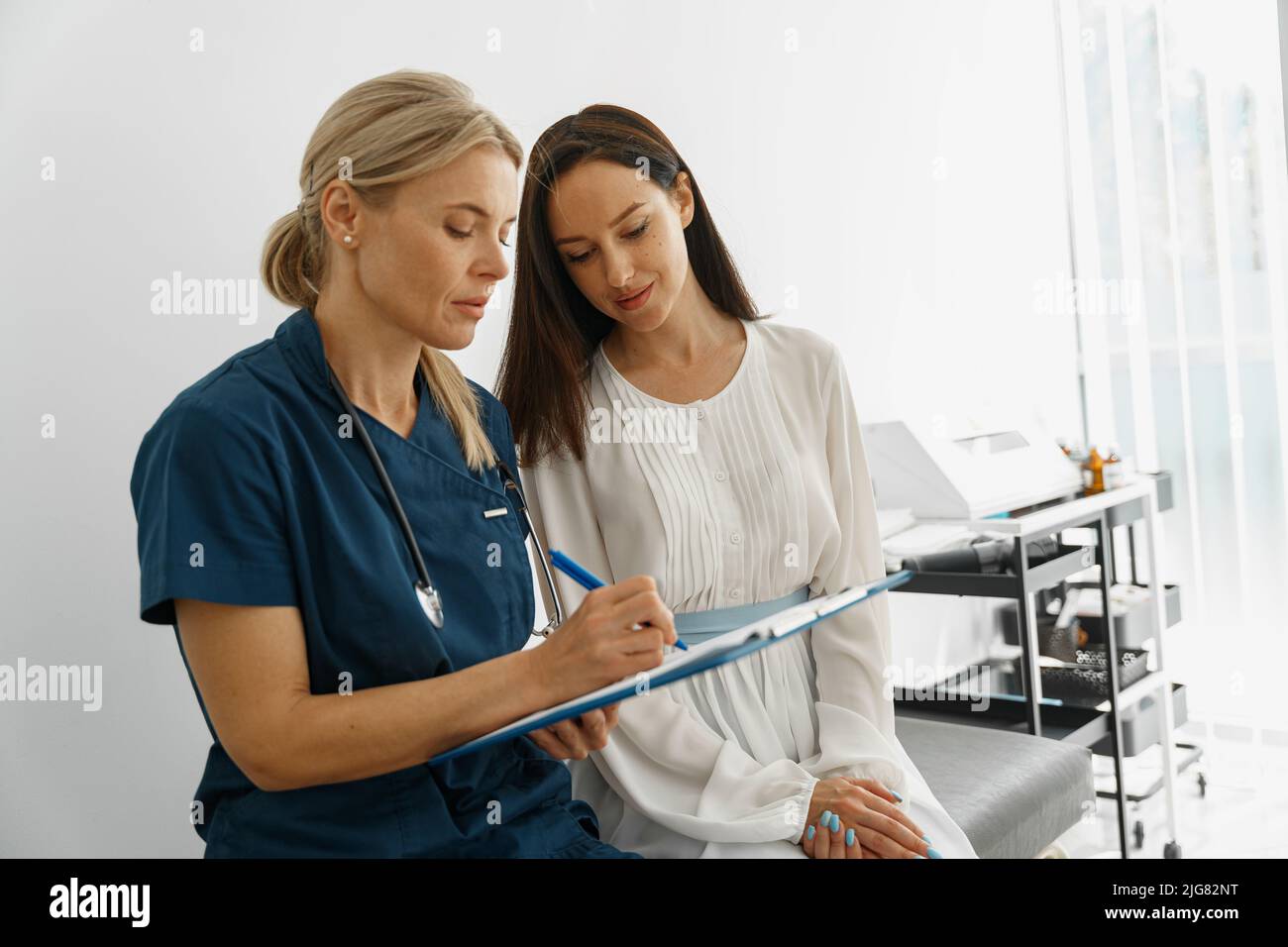 Smiling doctor fills out the medical report form on medical care of ...