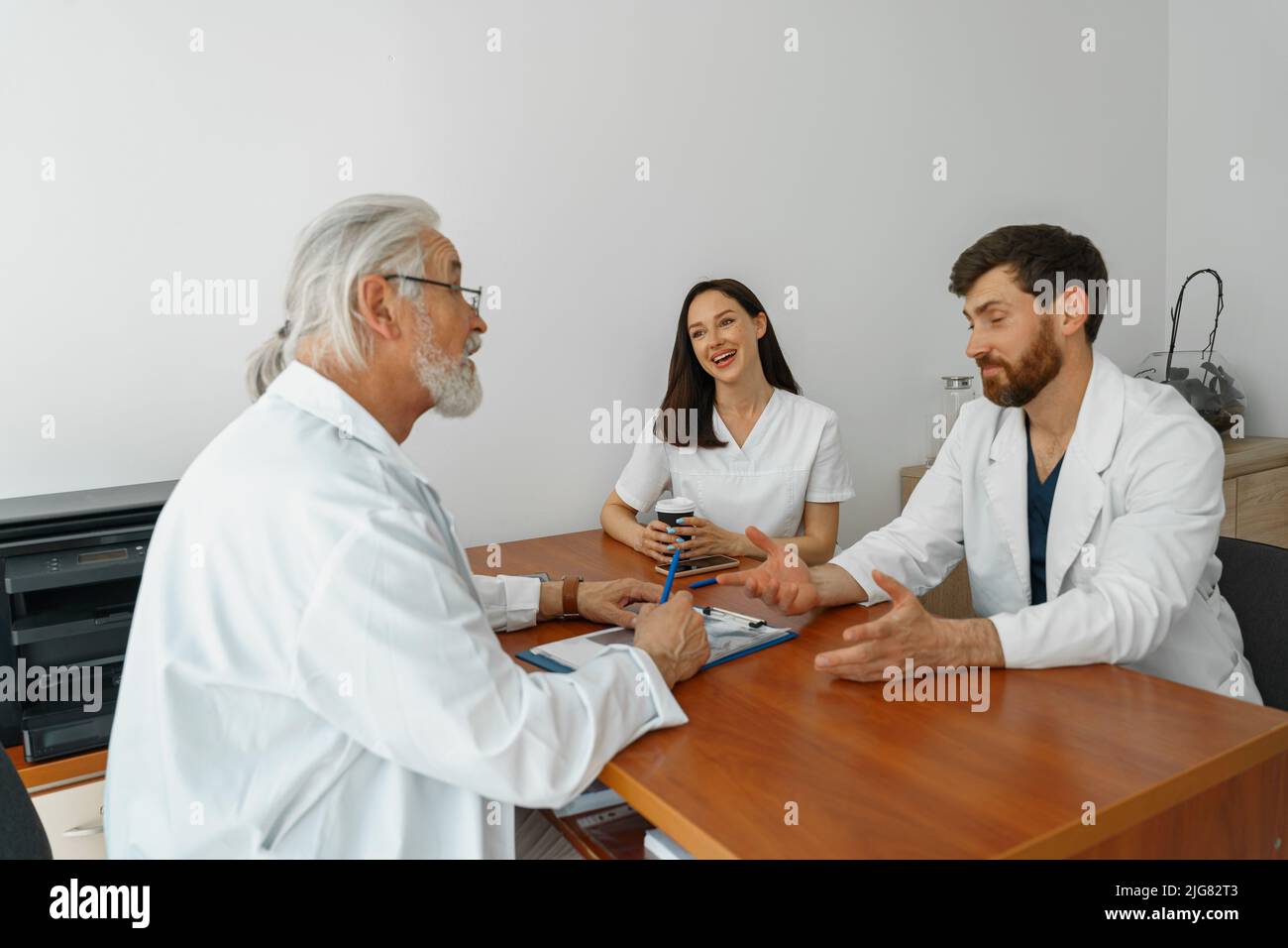 Group of doctors sitting at meeting table in conference room during ...