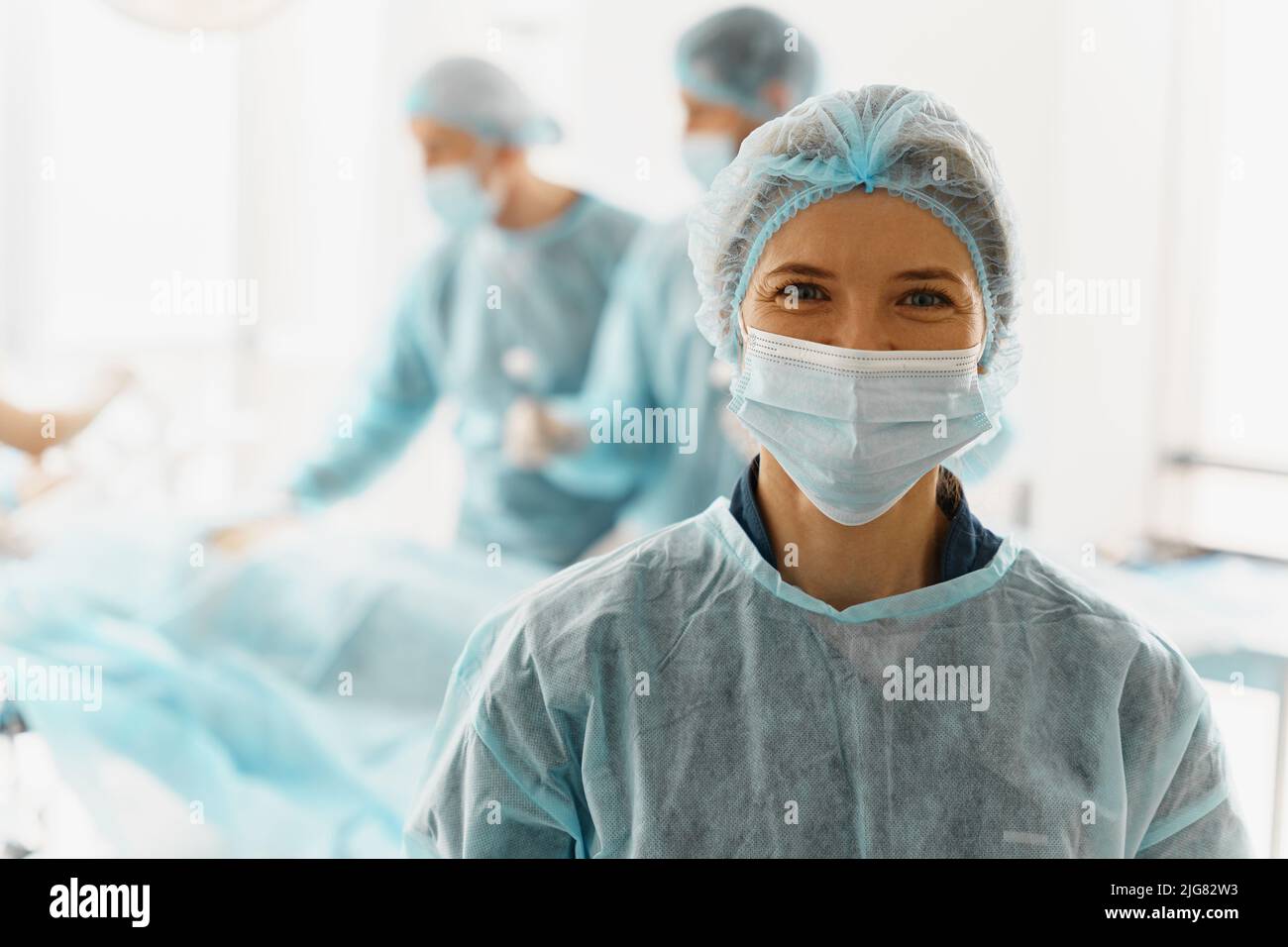 Portrait of female surgeon standing in operating room, ready to work on ...