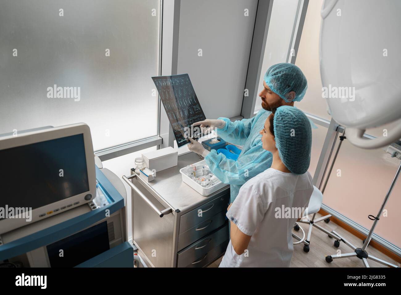Doctor and nurse in uniform look and discuss an X-ray or MRI scan of ...