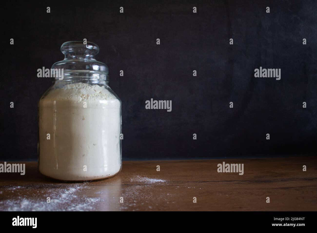 Flour in a jar on a wooden table with a dark background Stock Photo - Alamy