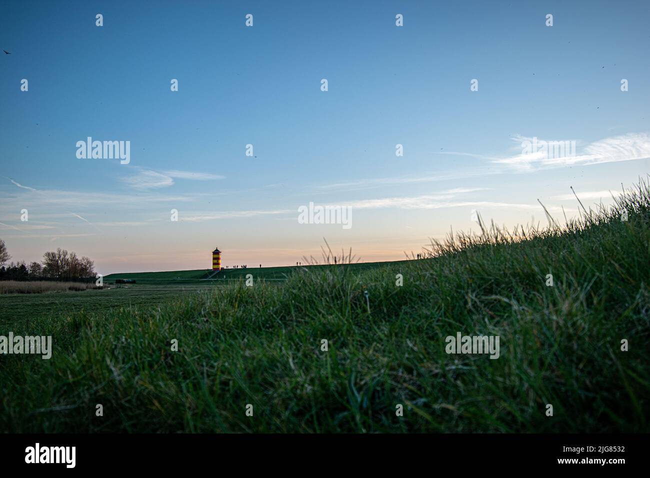 An old lighthouse, greenfield, and coast in Germany during sunset Stock ...