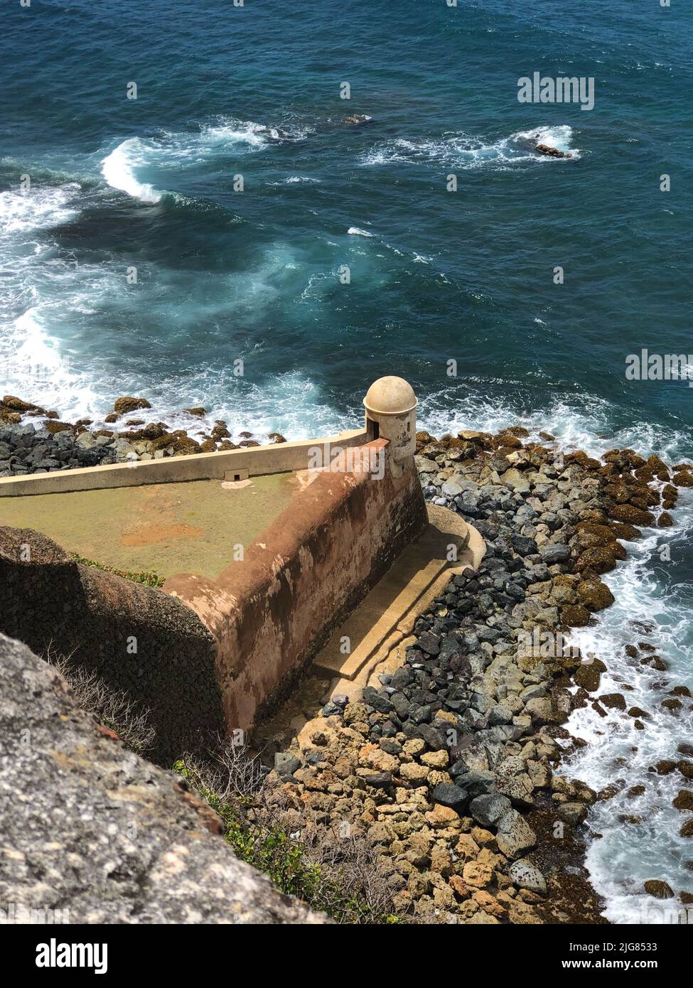 A vertical top view of sea waves reaching the stones of an old fort ...