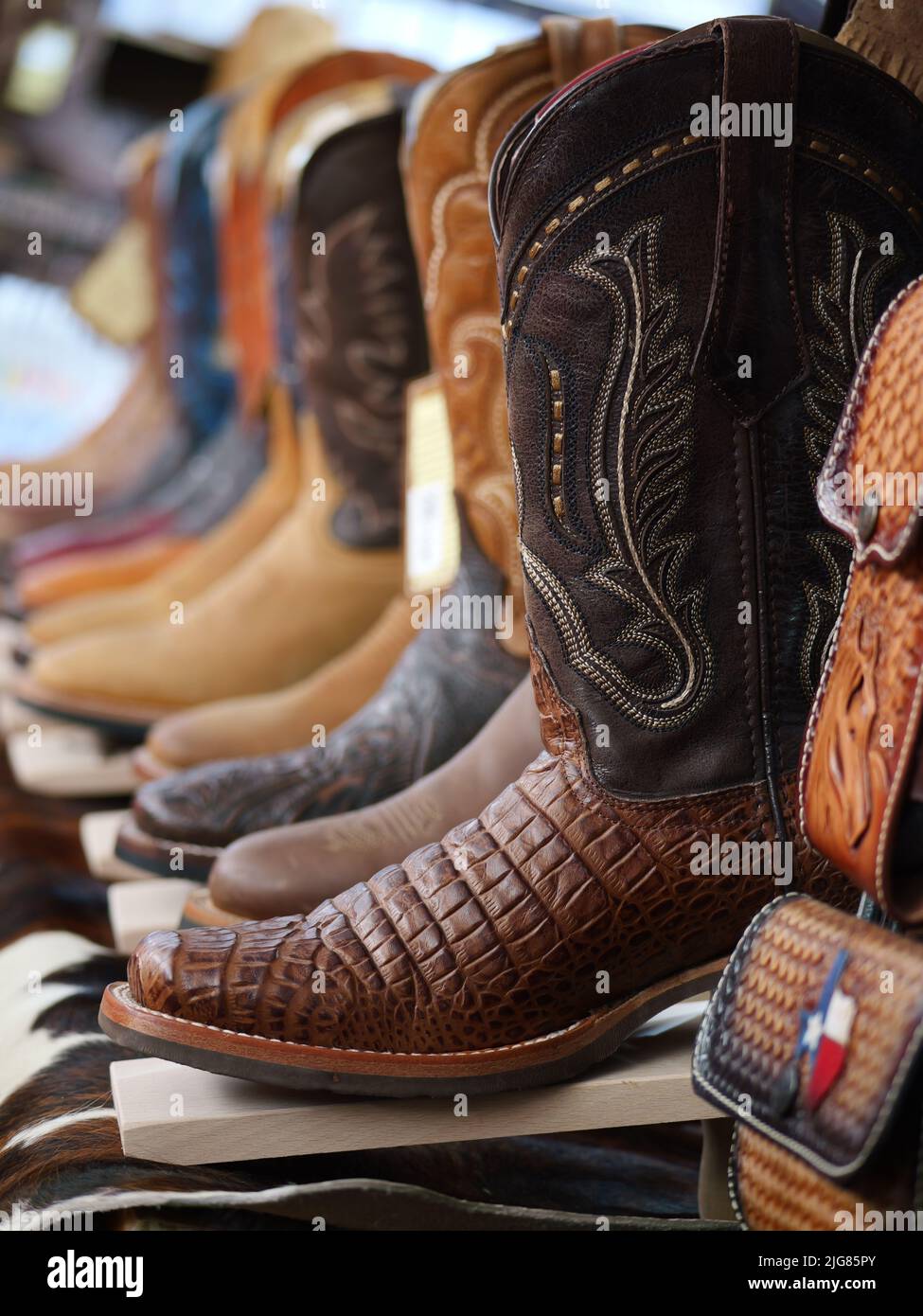 A vertical closeup shot of aligned cowboy boots on a shelf in a store ...