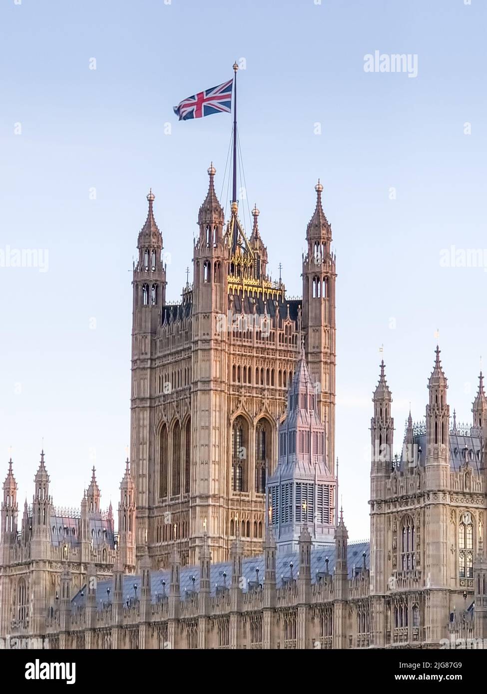 A vertical shot of the Palace of Westminster with the UK flag in London ...