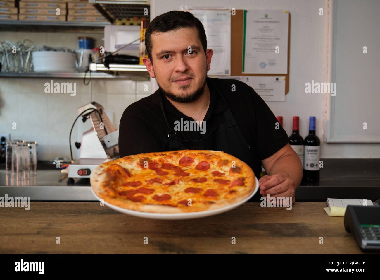 Latin male chef holding a freshly baked pepperoni pizza Stock Photo - Alamy