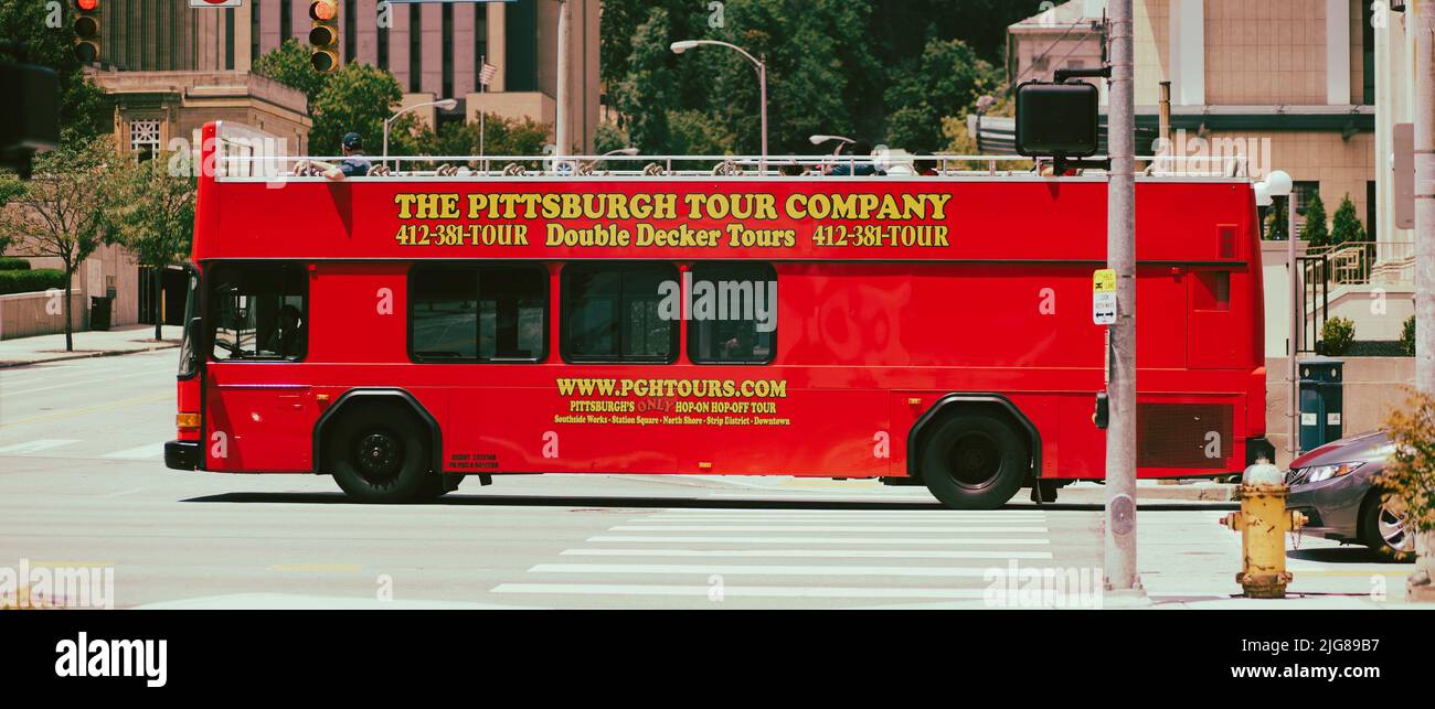 A red tour bus driving across the road Stock Photo - Alamy