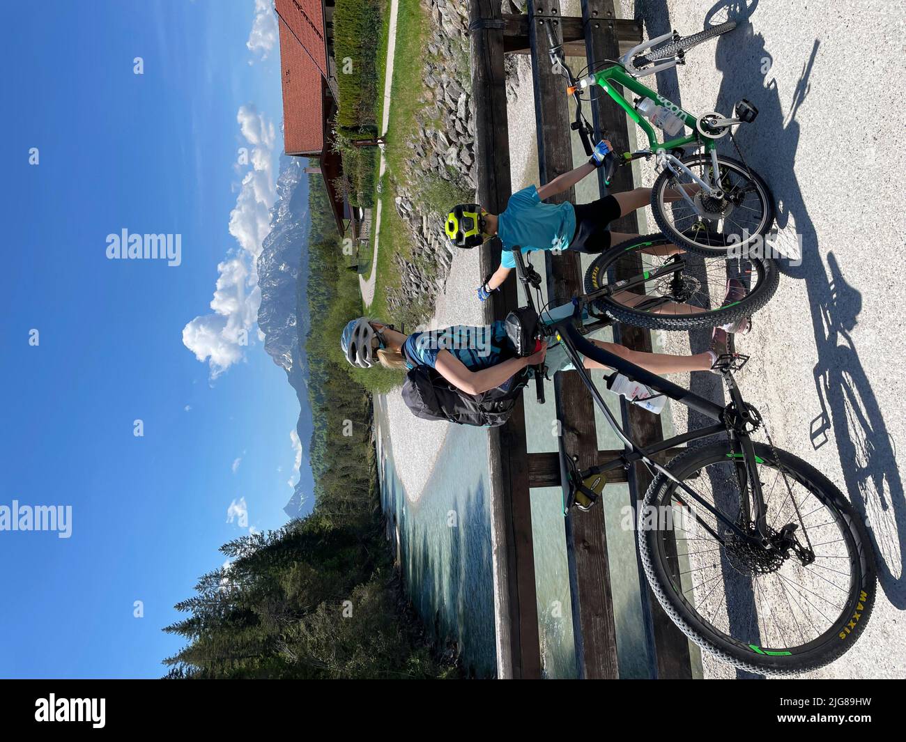 Mother with child cycling, Isar bridge, nature, mountains, blue sky ...