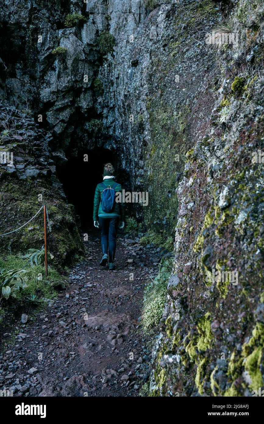 A back view of a woman with backpack entering the cave in Madeira ...