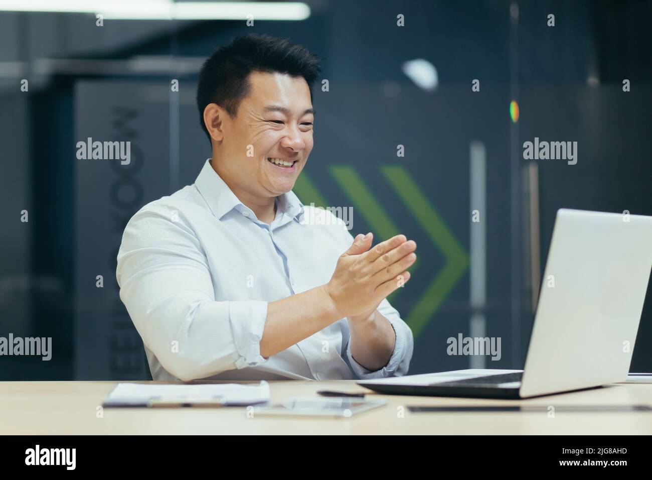 Satisfied Asian businessman director looking at laptop screen ...
