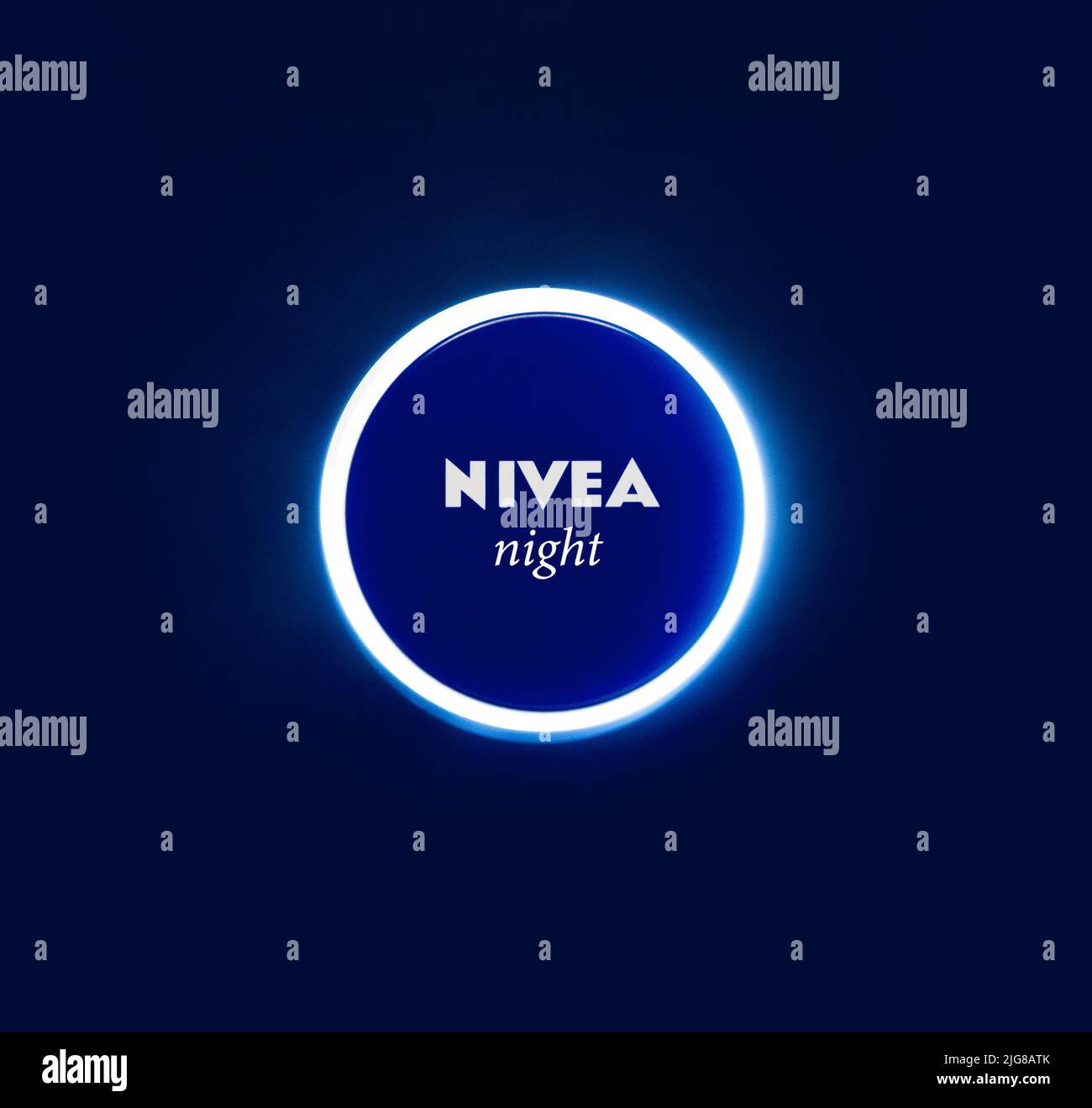 A closeup of a glowing Nivea night brand logo on a blue background ...