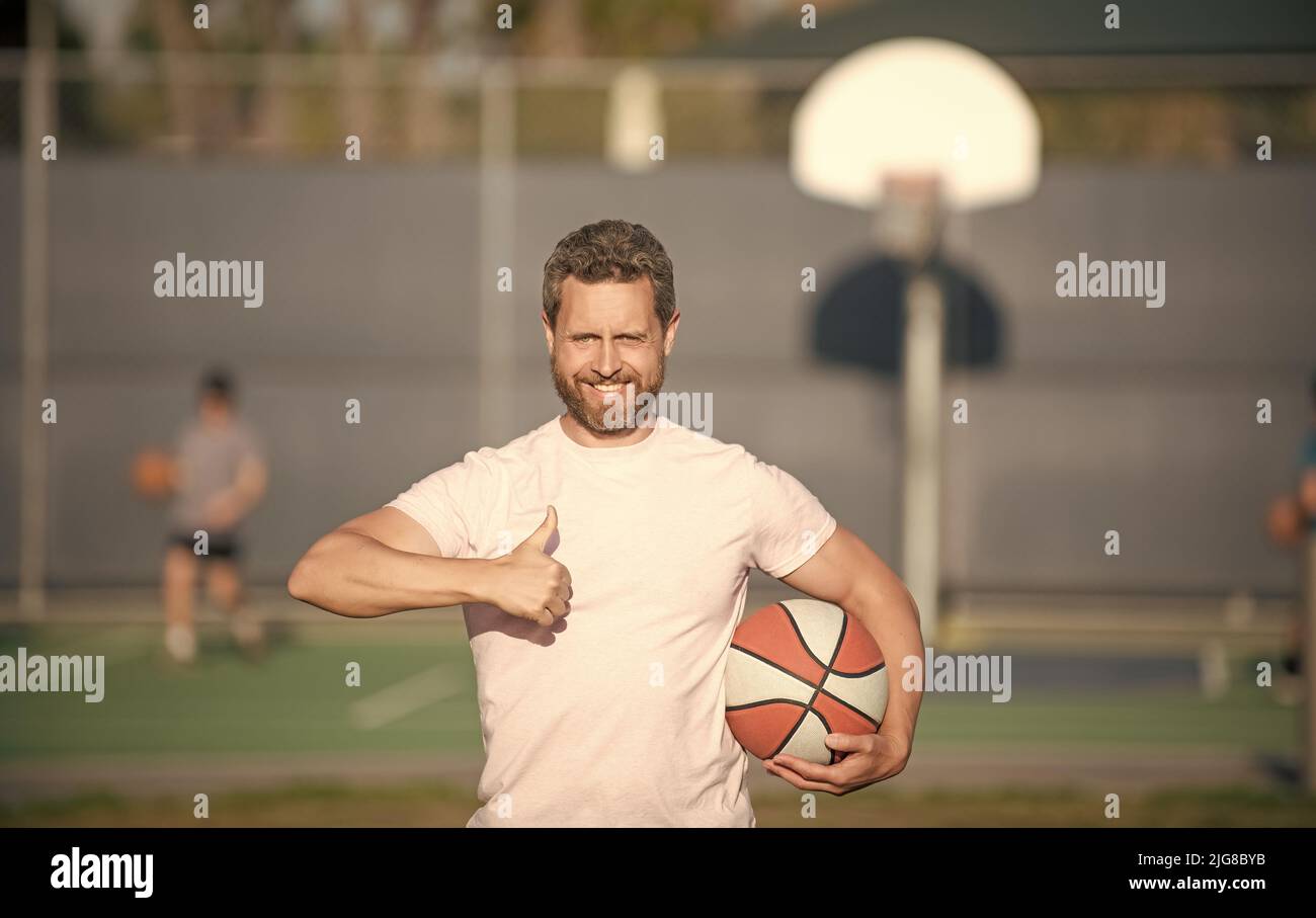 cheerful muscular man athlete basketball player hold ball outdoor ...
