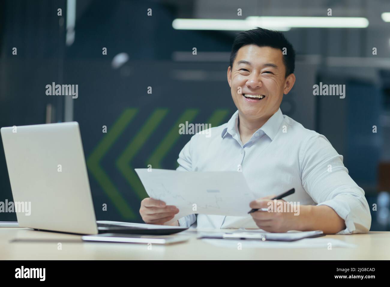 Portrait of successful Asian investor behind paperwork, businessman ...