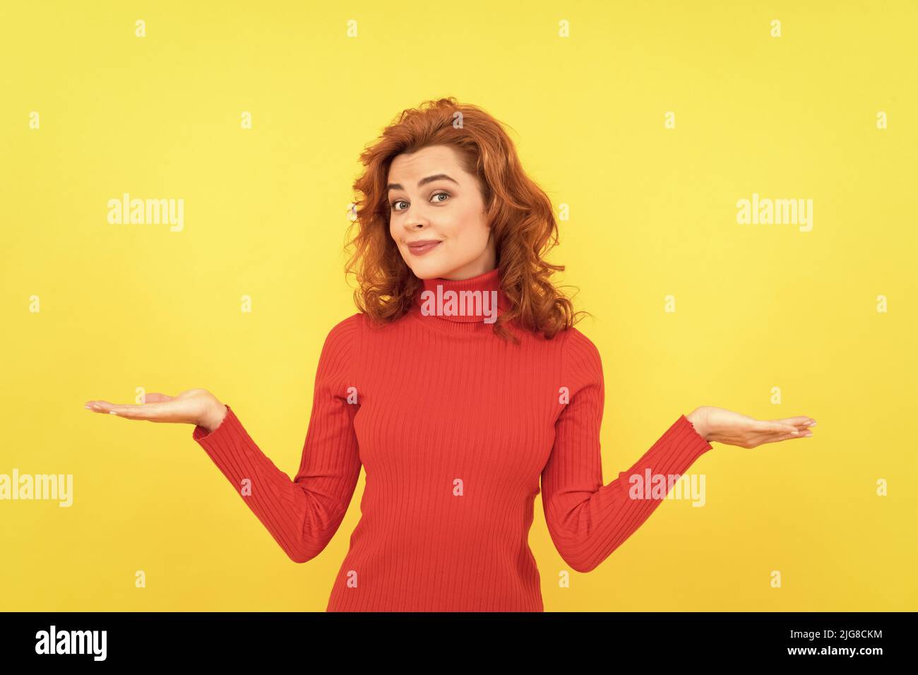 cheerful redhead woman making choice presenting product with copy space ...