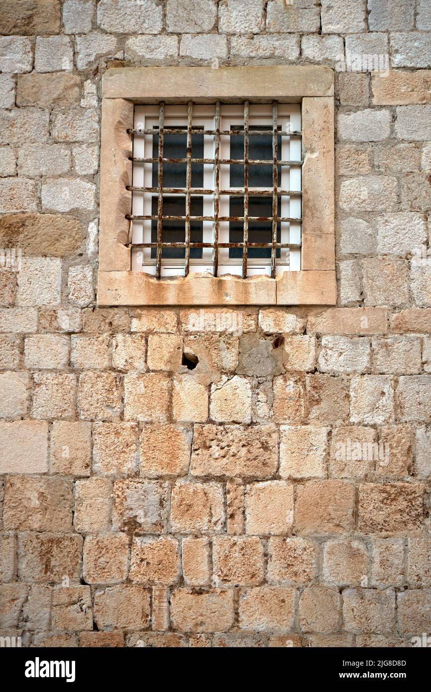A vertical shot of building wall with window in front of window bars ...