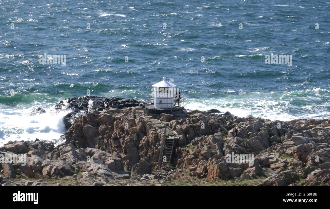 A high angle shot of a person at a lighthouse on a rocky beach against ...