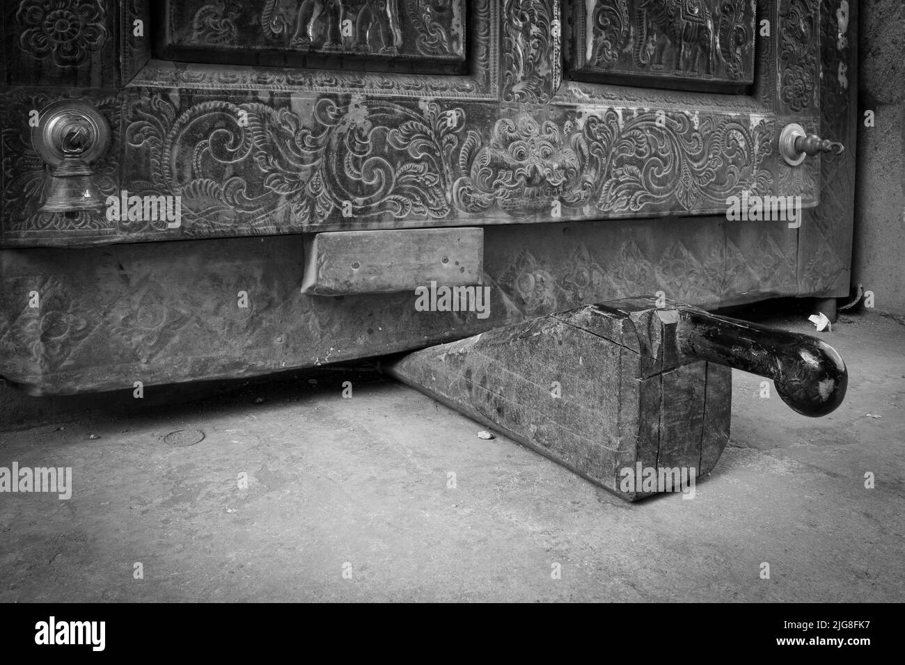A grayscale shot of wooden piece blocking an old door from opening ...
