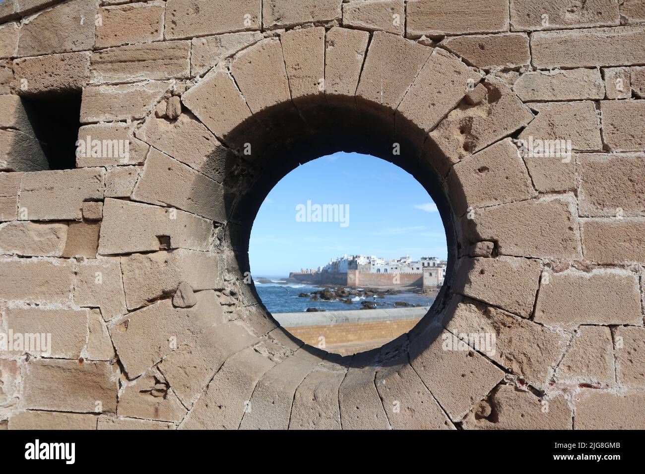 A close-up shot through a round hole window to buildings by the sea ...