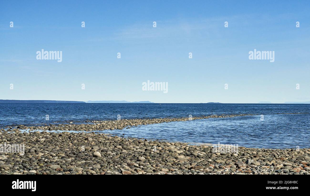 View of a rippled deep blue ocean from a rocky beach with islands in ...