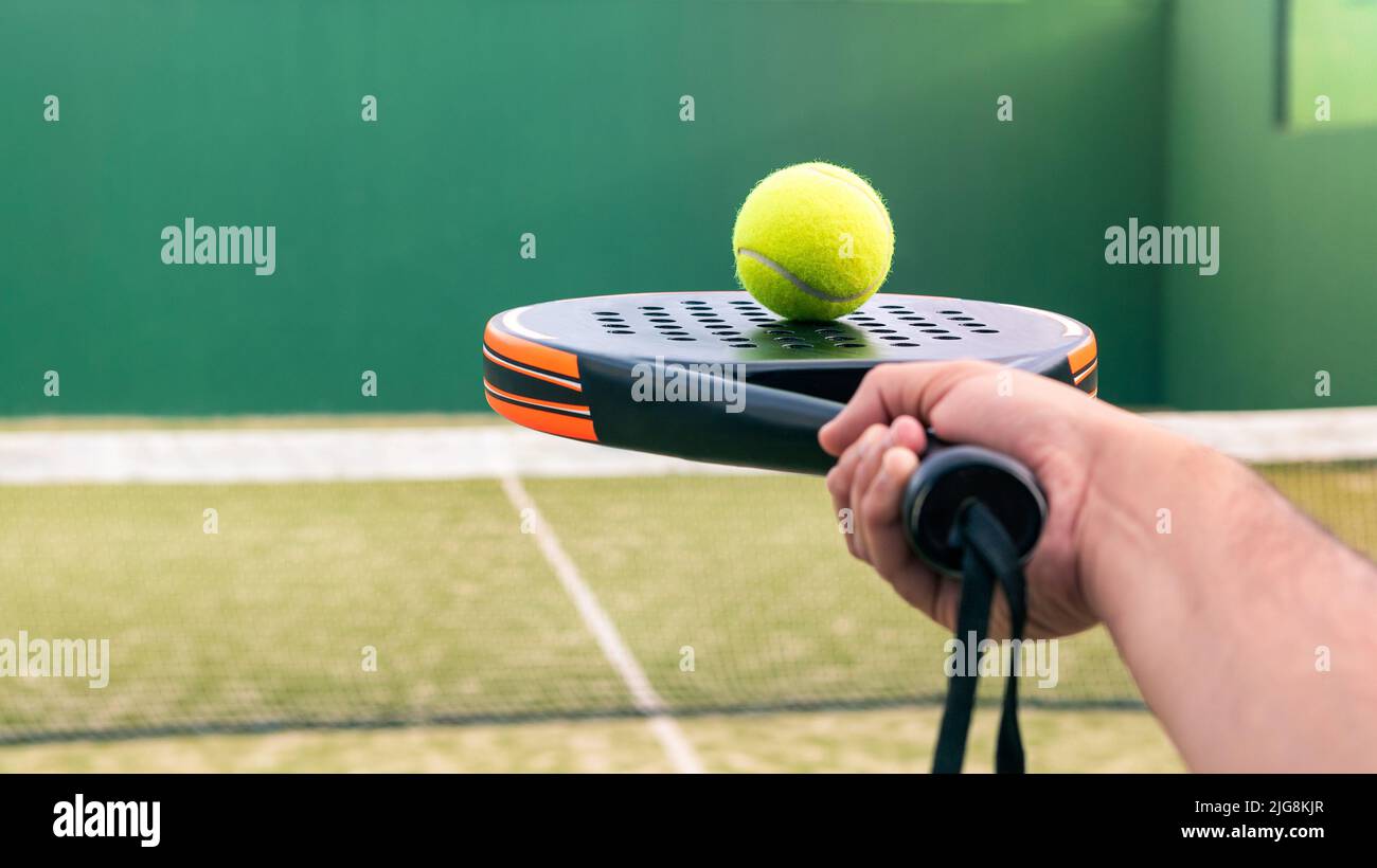 One caucasian man with the ball on top of the padel racket at a green ...